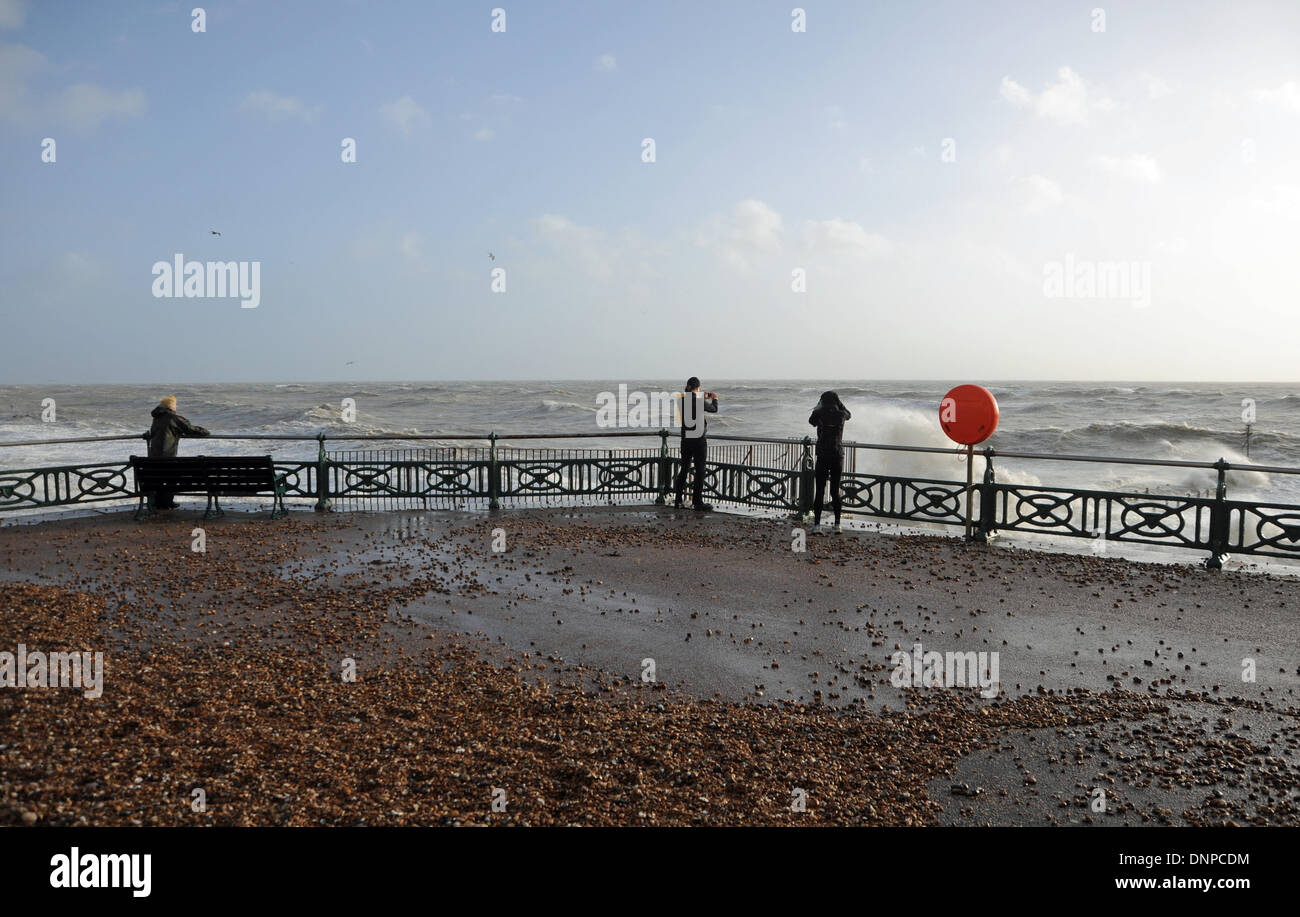 A couple get caught by a wave breaking over the promenade in Hove today ...