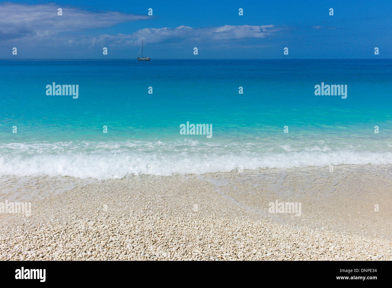 Turquoise blue sea with waves, white pebbles and yacht at Myrtos Beach ...