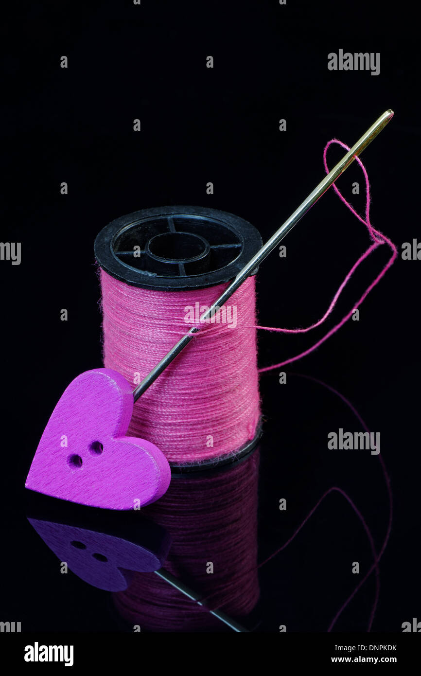 Heart shaped button with needle and thread symbolising love and ...