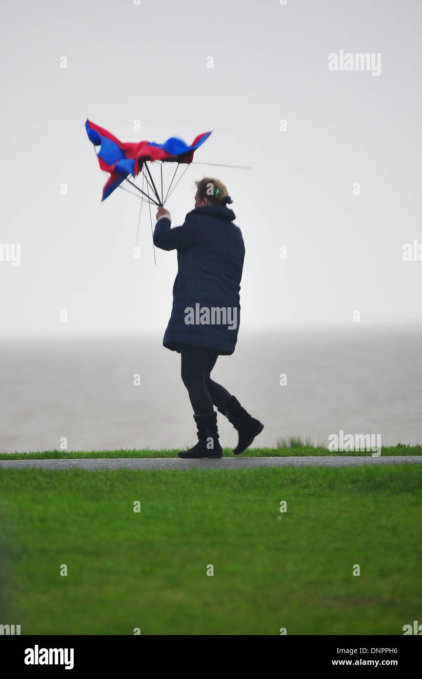 A woman battling against the wind with an umbrella in Barry Island ...