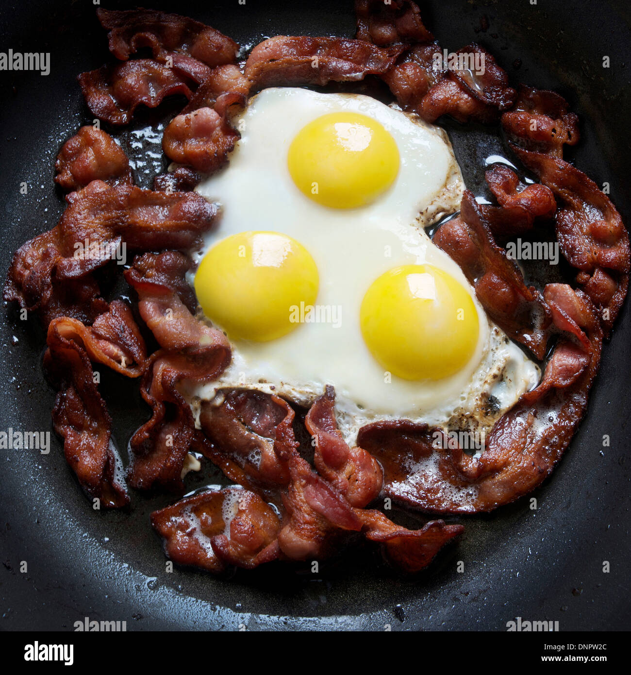 greasy frying pan full of bacon and eggs Stock Photo - Alamy