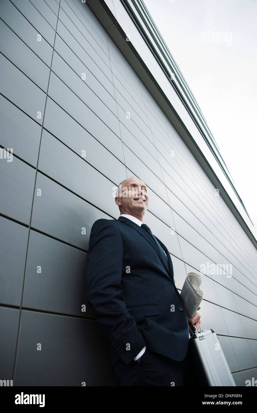 Portrait of businessman leaning against wall of building, Mannheim ...