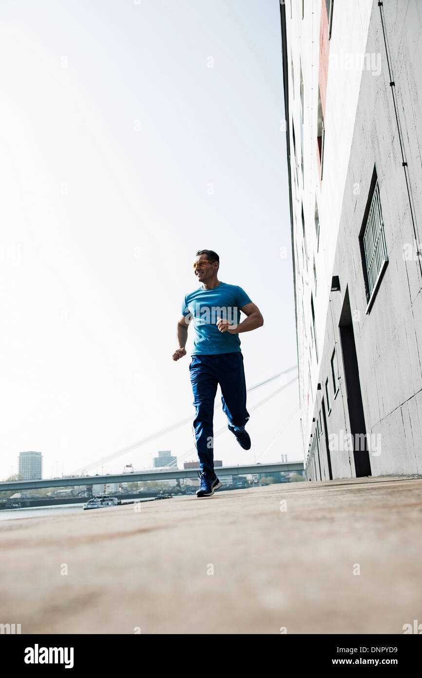 Mature man running along loading dock in front of warehouse, Mannheim ...