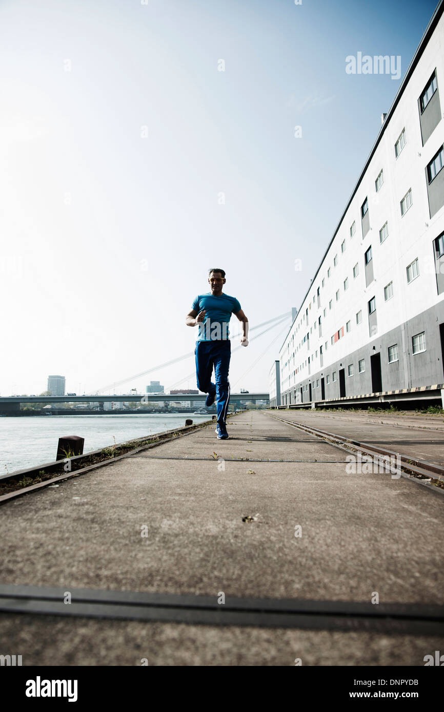 Mature man running along loading dock in front of warehouse, Mannheim ...