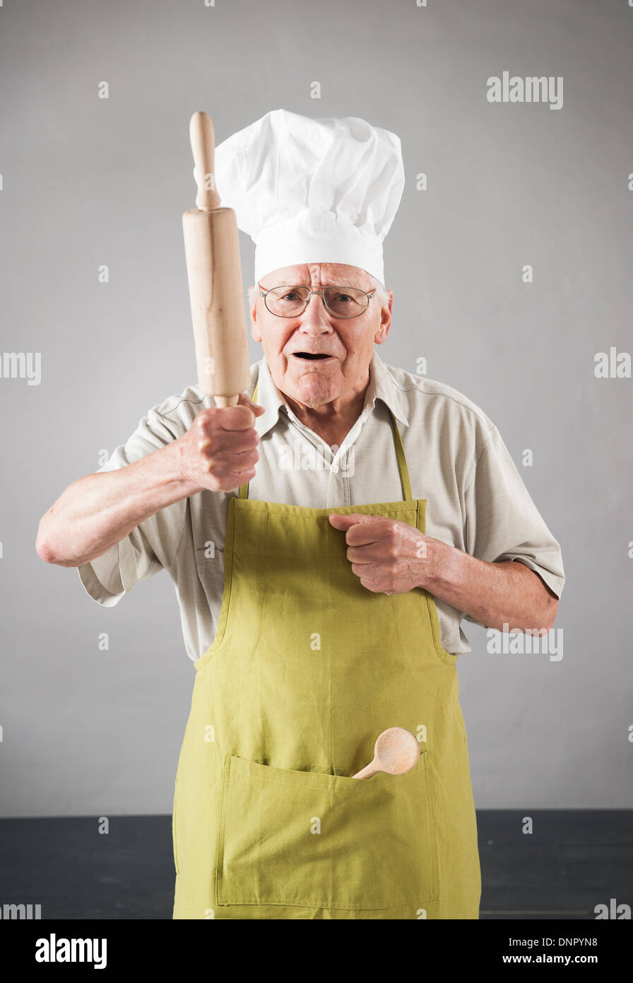 Elderly Man wearing Apron and Chef's Hat holding Rolling Pin in Studio ...