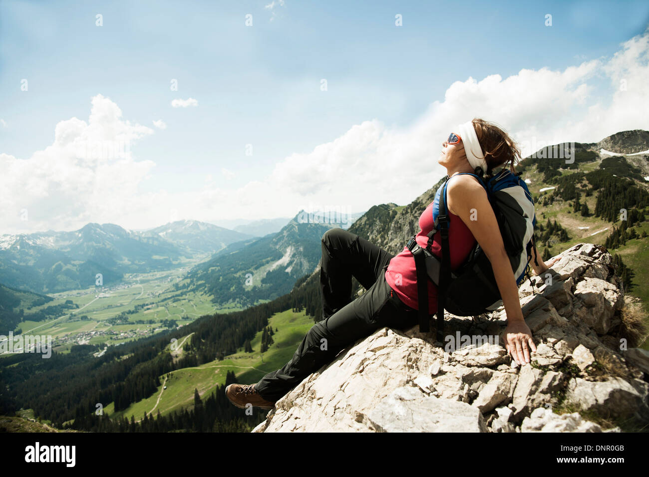 Mature woman sitting on cliff, hiking in mountains, Tannheim Valley ...