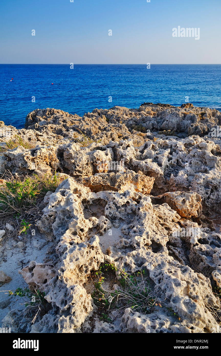 The setting sun shines on a rock formation at the Nissi Beach in Ayia ...