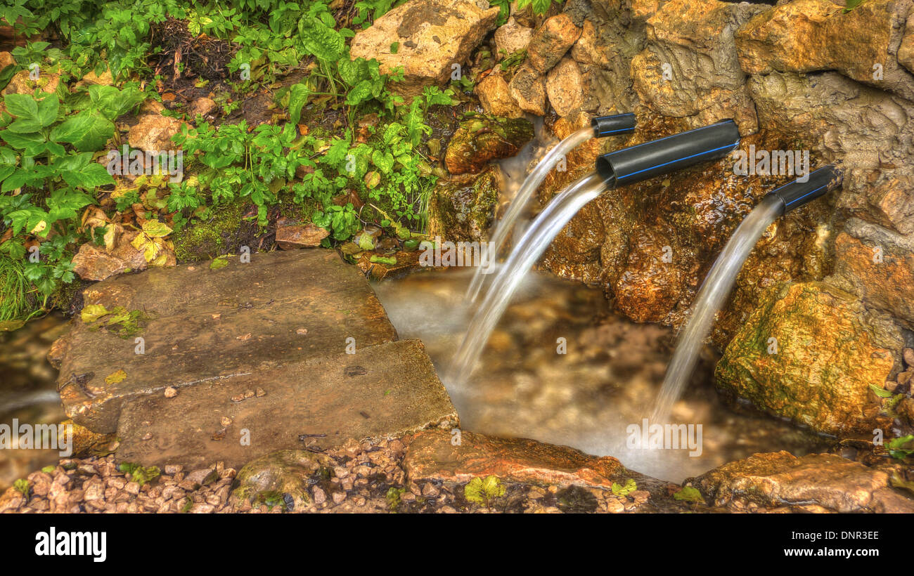 HDR photo of spring water flowing out of 3 plastic pipes and its ...