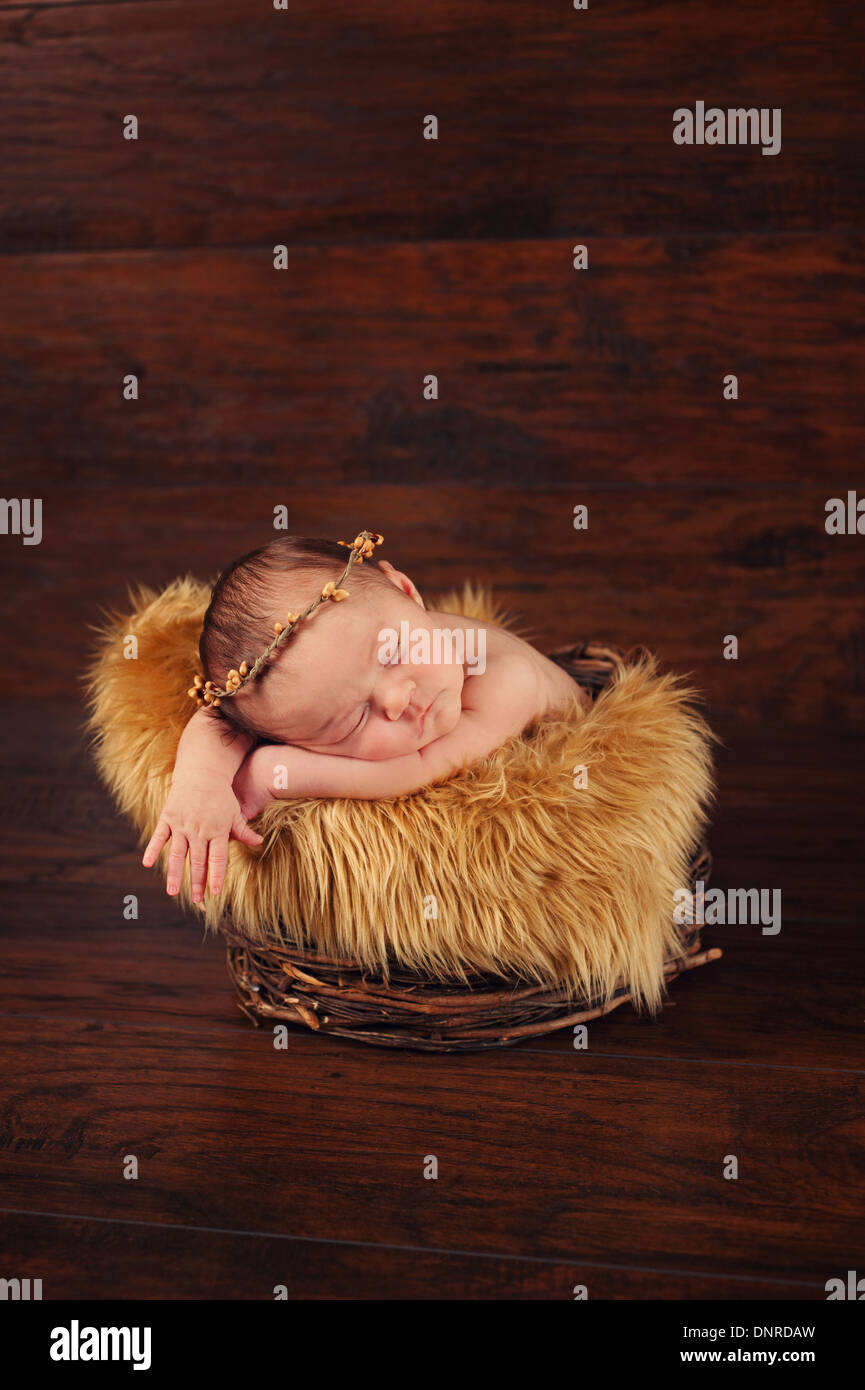 A two week old newborn baby sleeping in a twig basket and wearing a ...