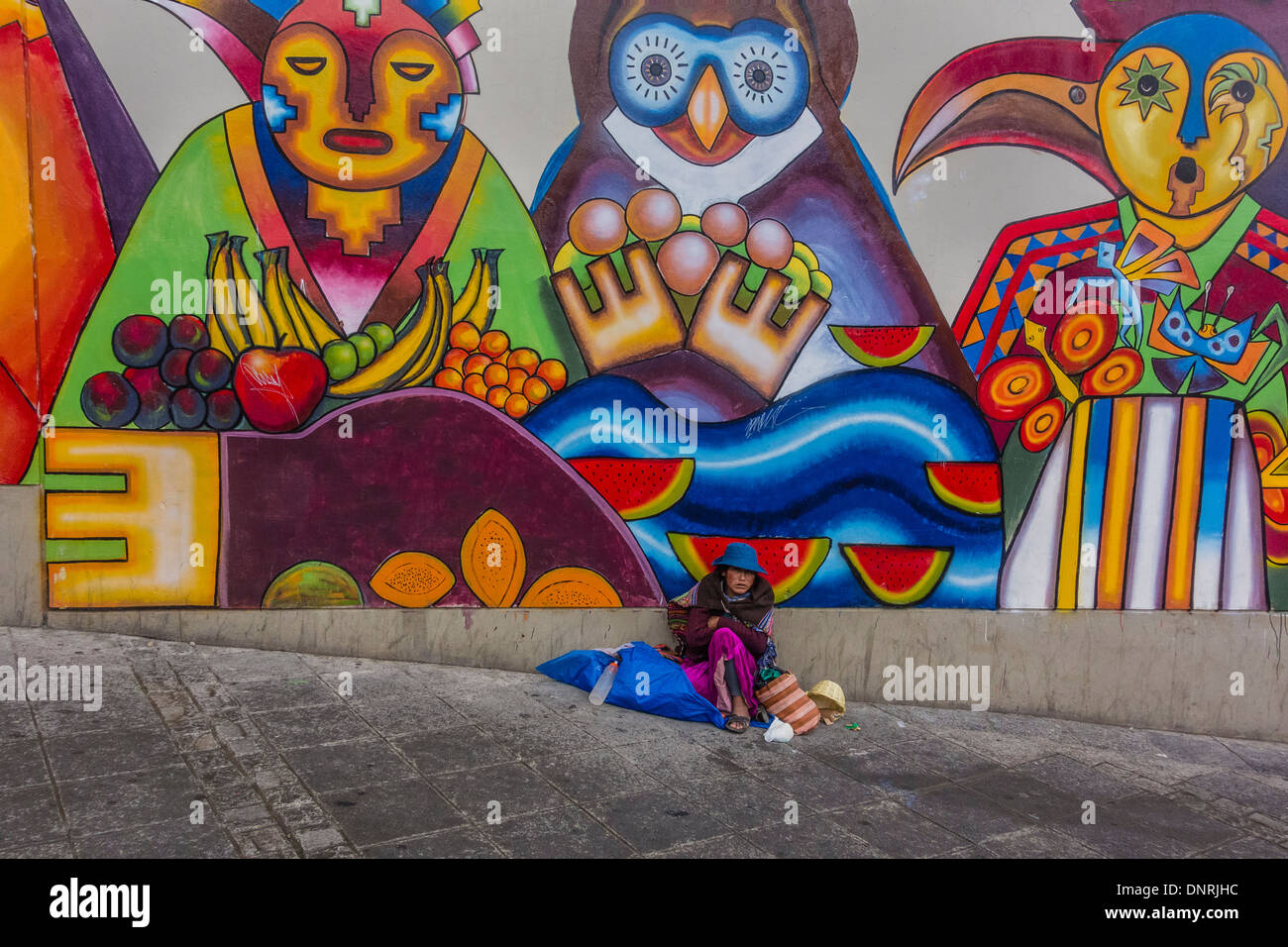 An older indigenous Bolivian woman sits on the sidewalk in front of a ...