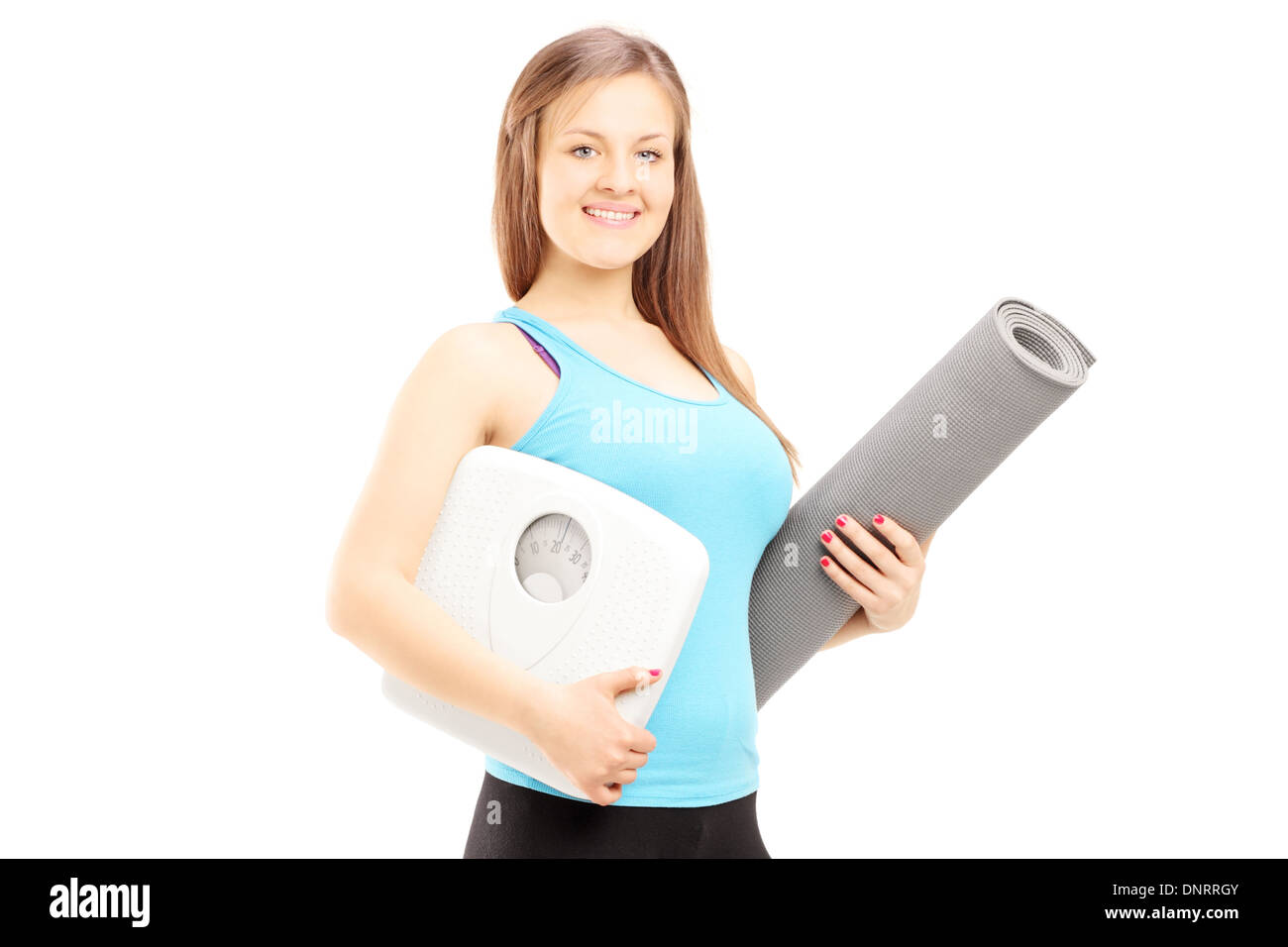 Smiling female athlete holding a weight scale and mat Stock Photo - Alamy