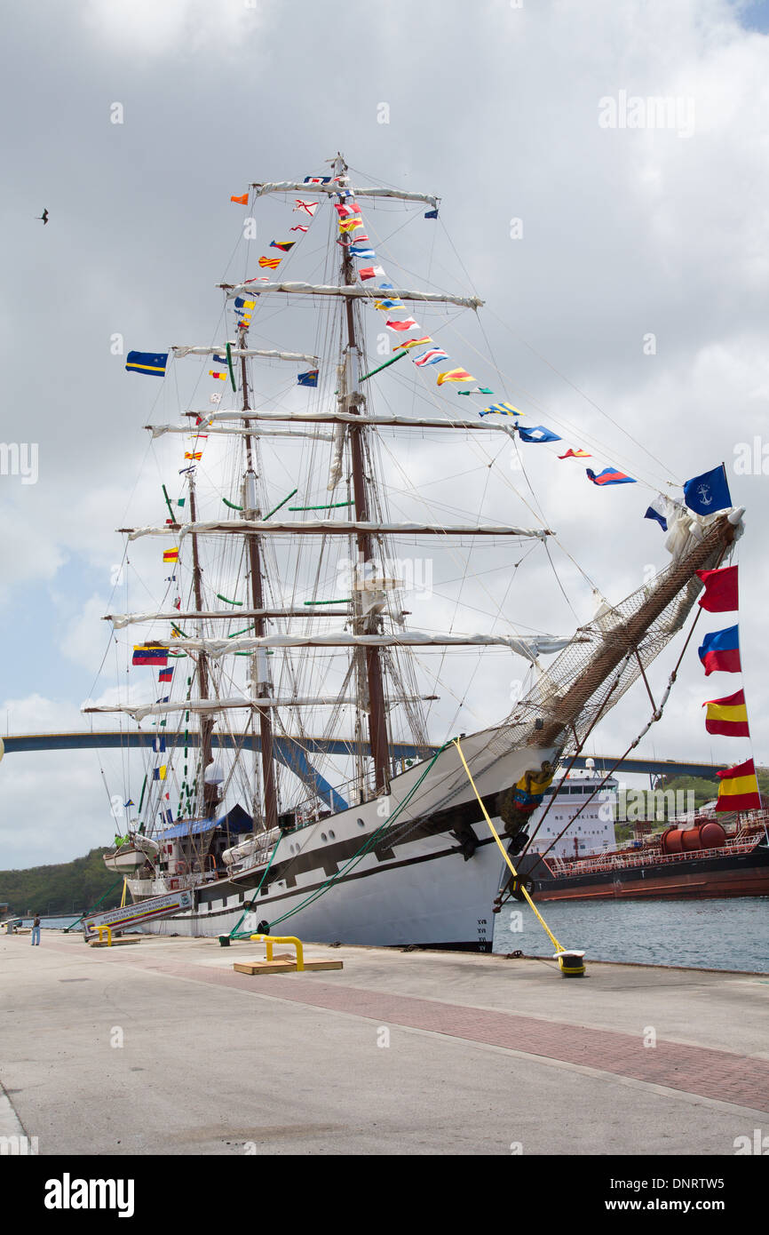 An historic square rigged sailing ship sits moored on the dock of ...