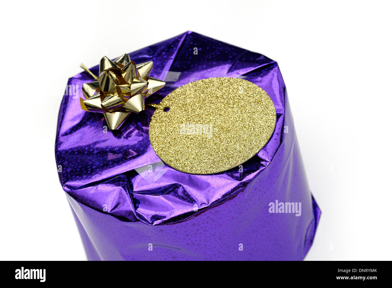 Christmas present gift with gold label and bow in purple wrapping paper ...