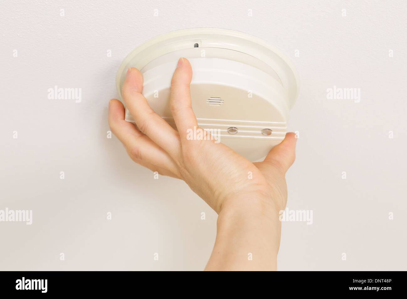 Horizontal photo of female hands putting home smoke detector together ...
