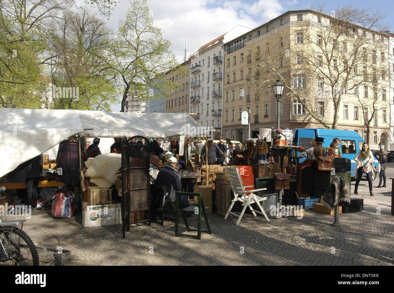 2 men vendors 30s 40s sitting market stall table centre foreground hi ...