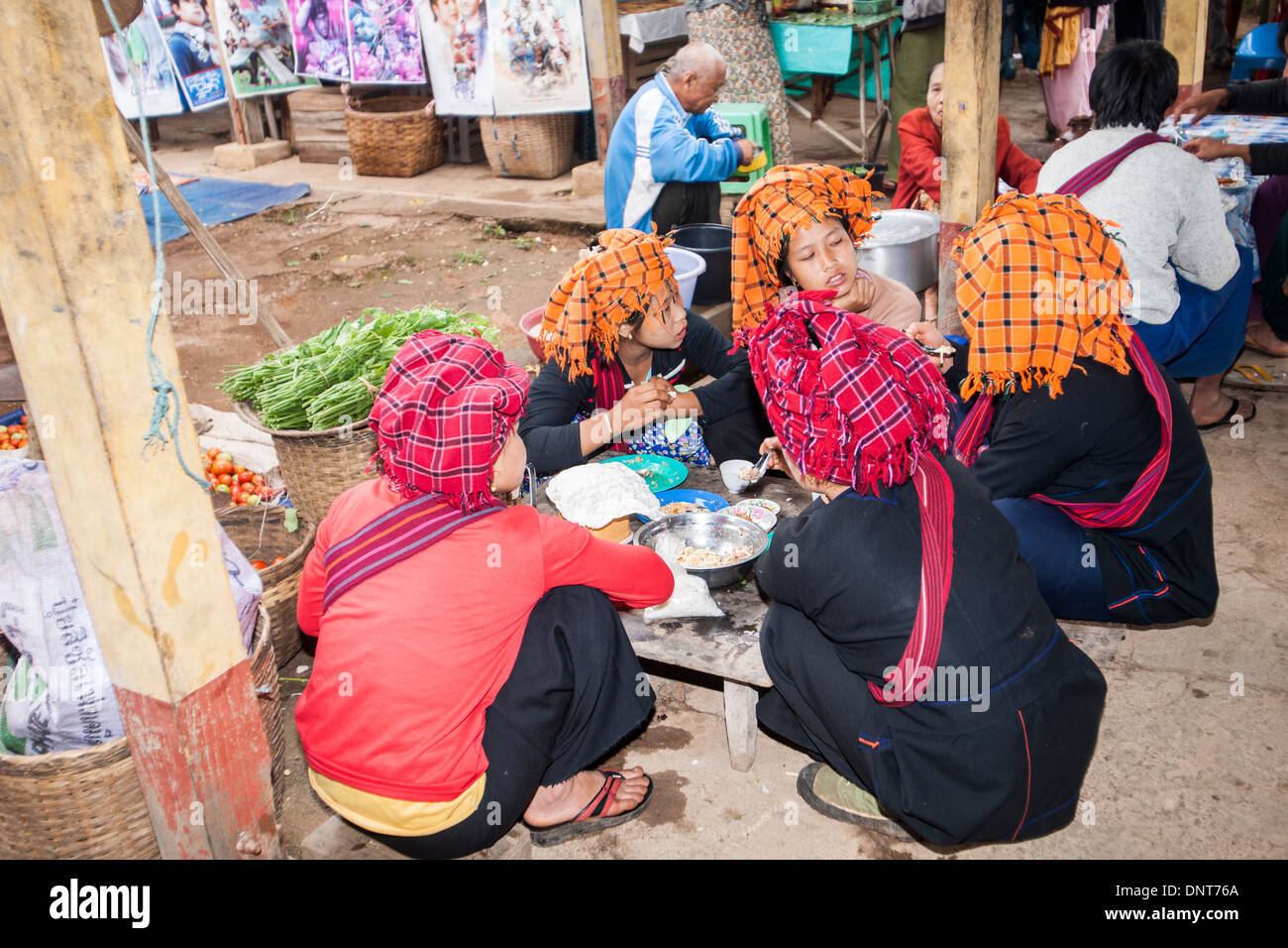 Women of the Pa O Tribe crouching and eating at the market wearing ...