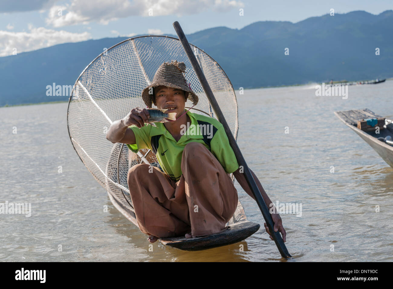 Traditional fisherman on Inle Lake proudly holds small fish caught in ...