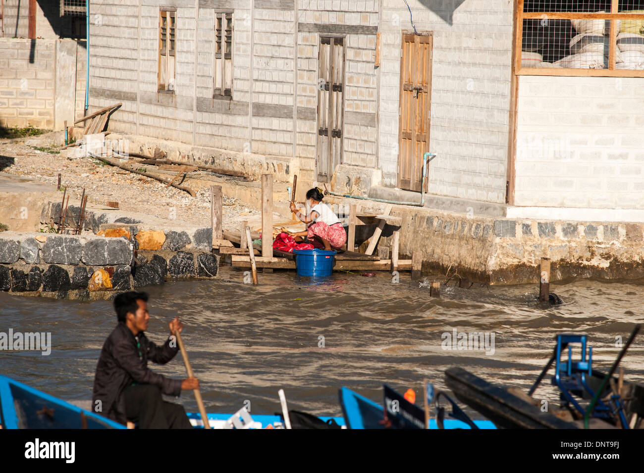 Woman washes clothes by the edge of Inle Lake across from the docks at ...