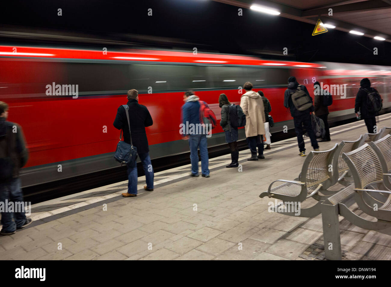 People standing on platform at night as red train passes bye, Munich ...