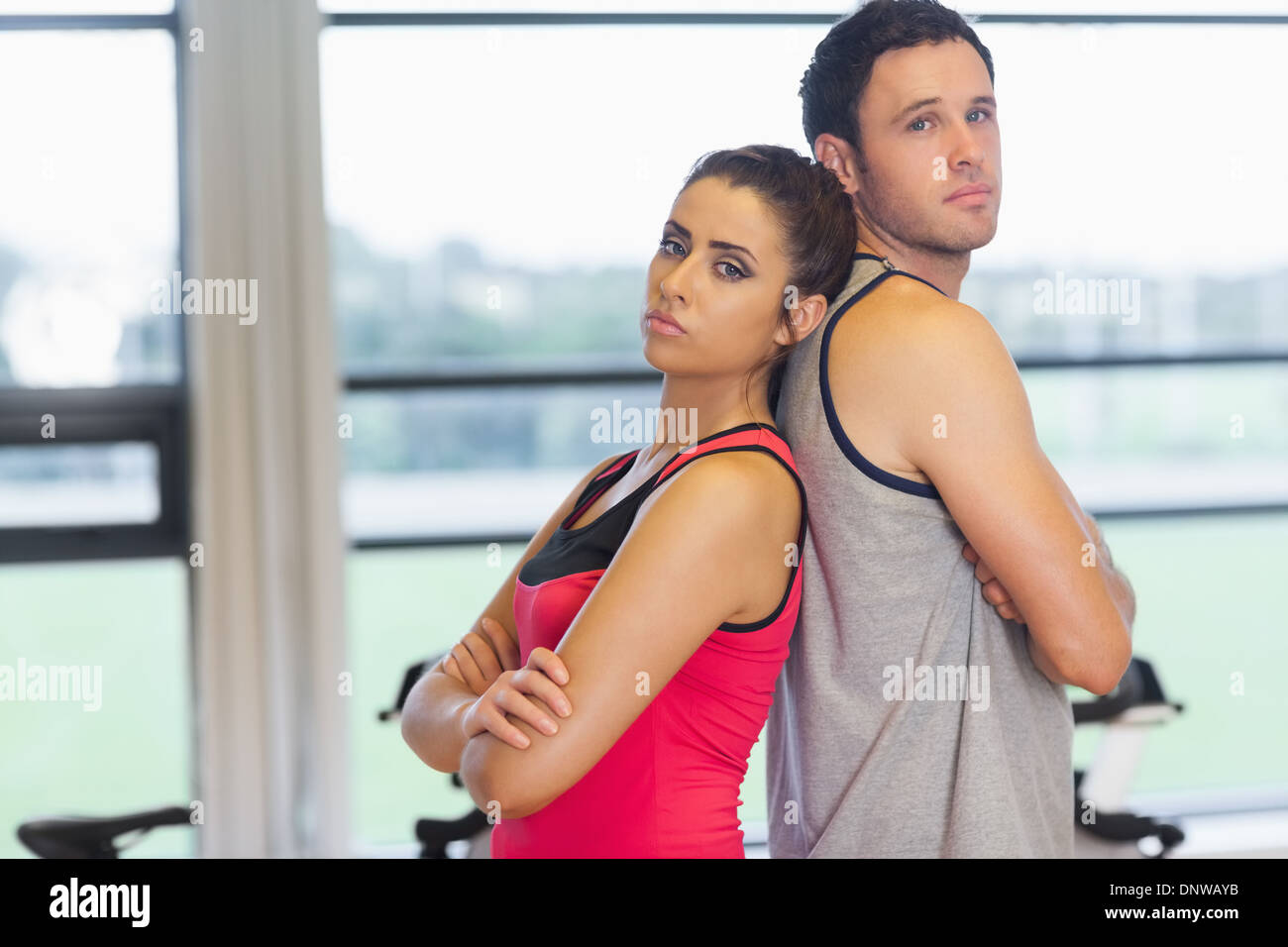 Serious woman and man standing back to back in gym Stock Photo - Alamy
