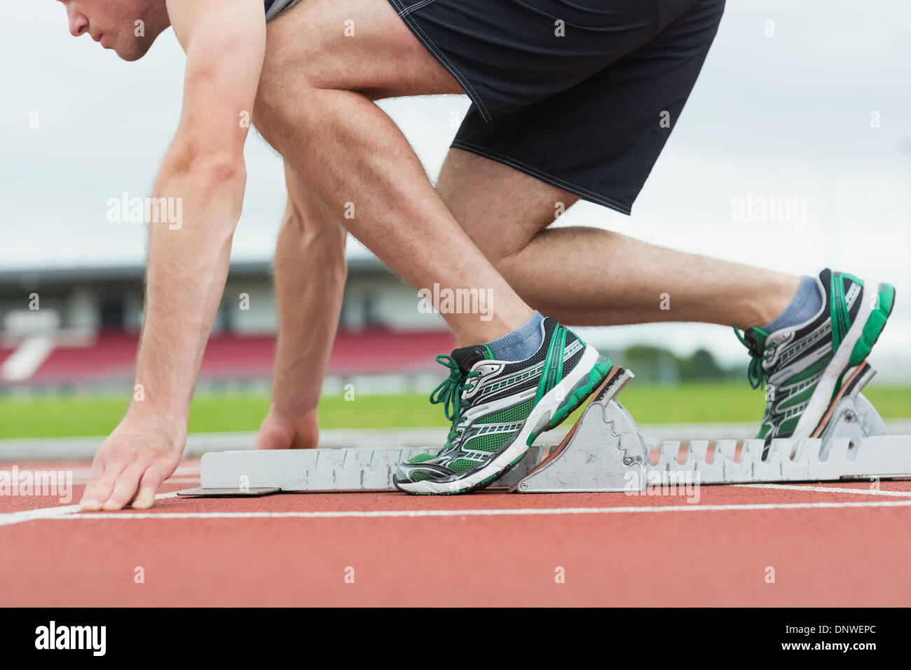 Side view of a man ready to race on running trac Stock Photo - Alamy