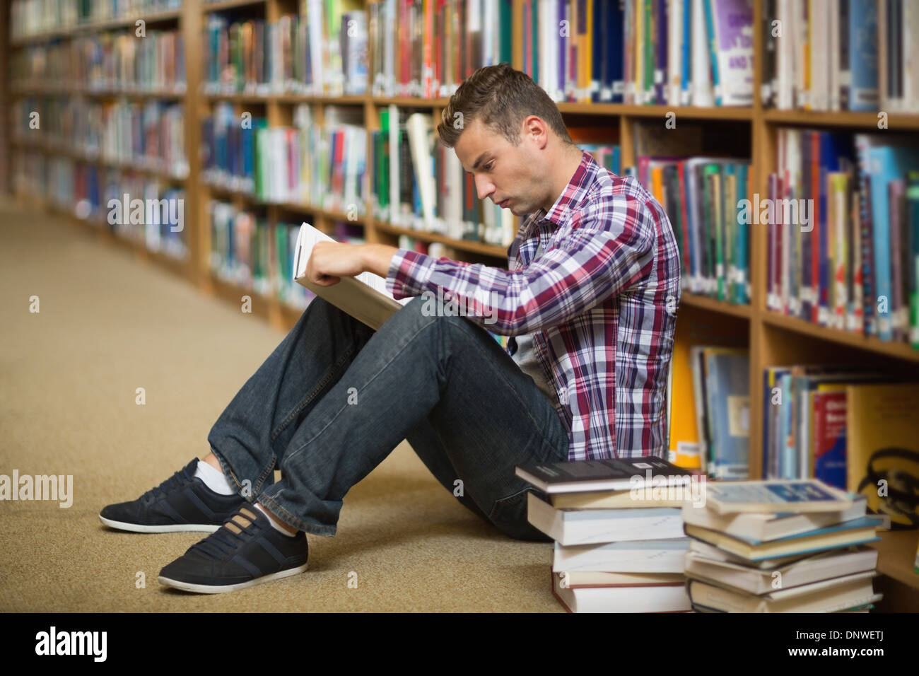 Student sitting on library floor reading Stock Photo - Alamy