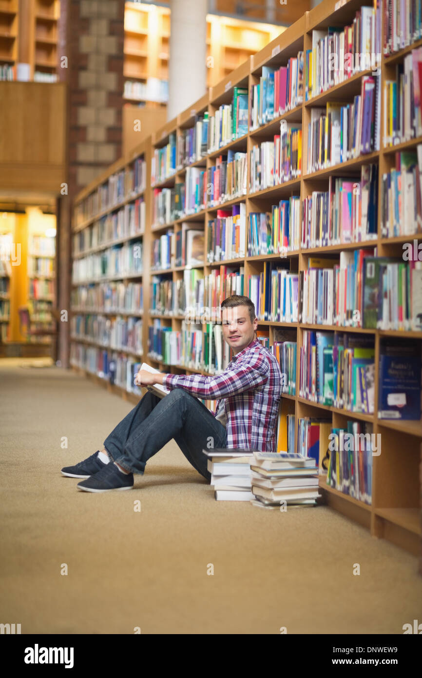 Cheerful student sitting on library floor reading Stock Photo - Alamy