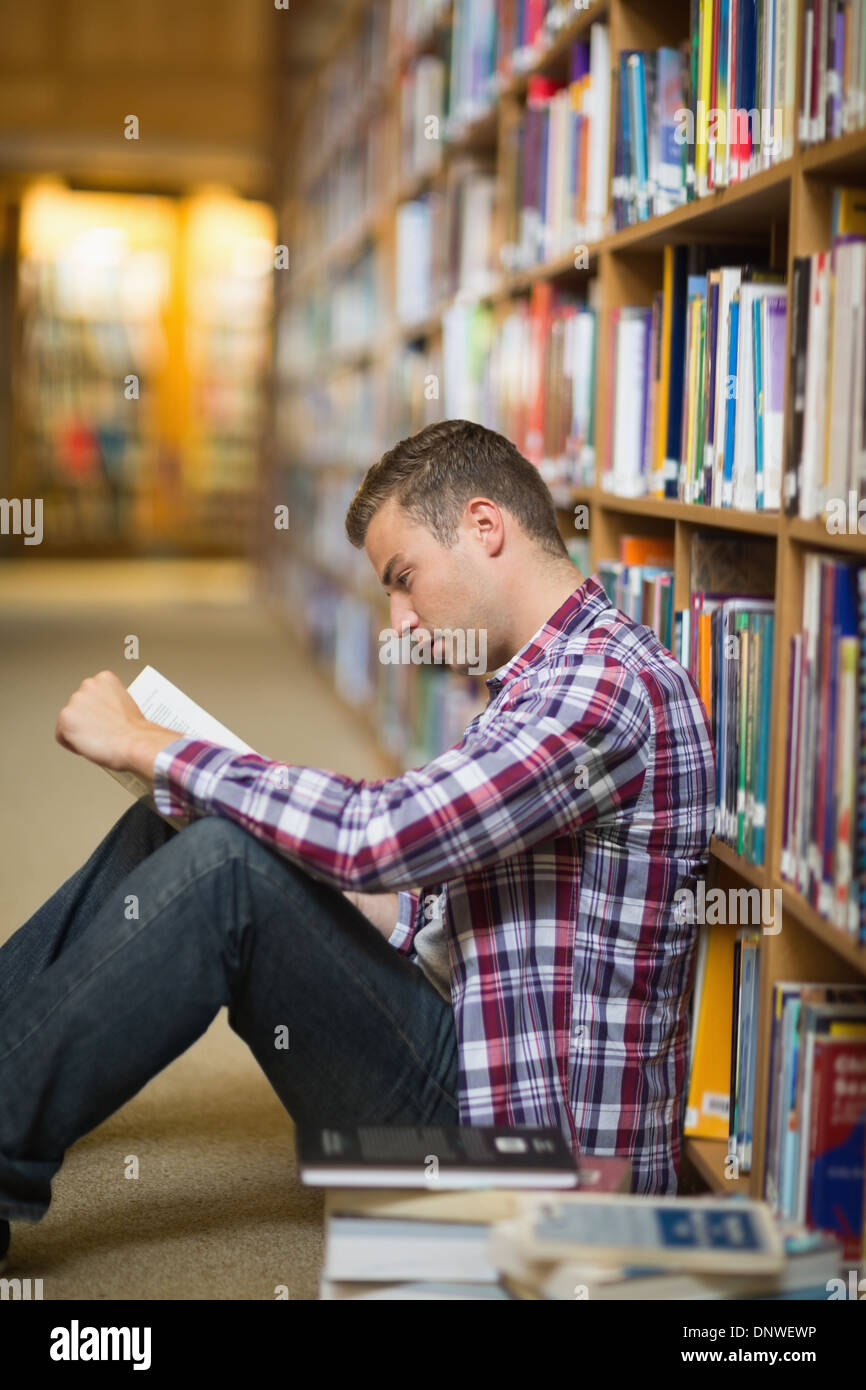 Focused student sitting on library floor reading Stock Photo - Alamy