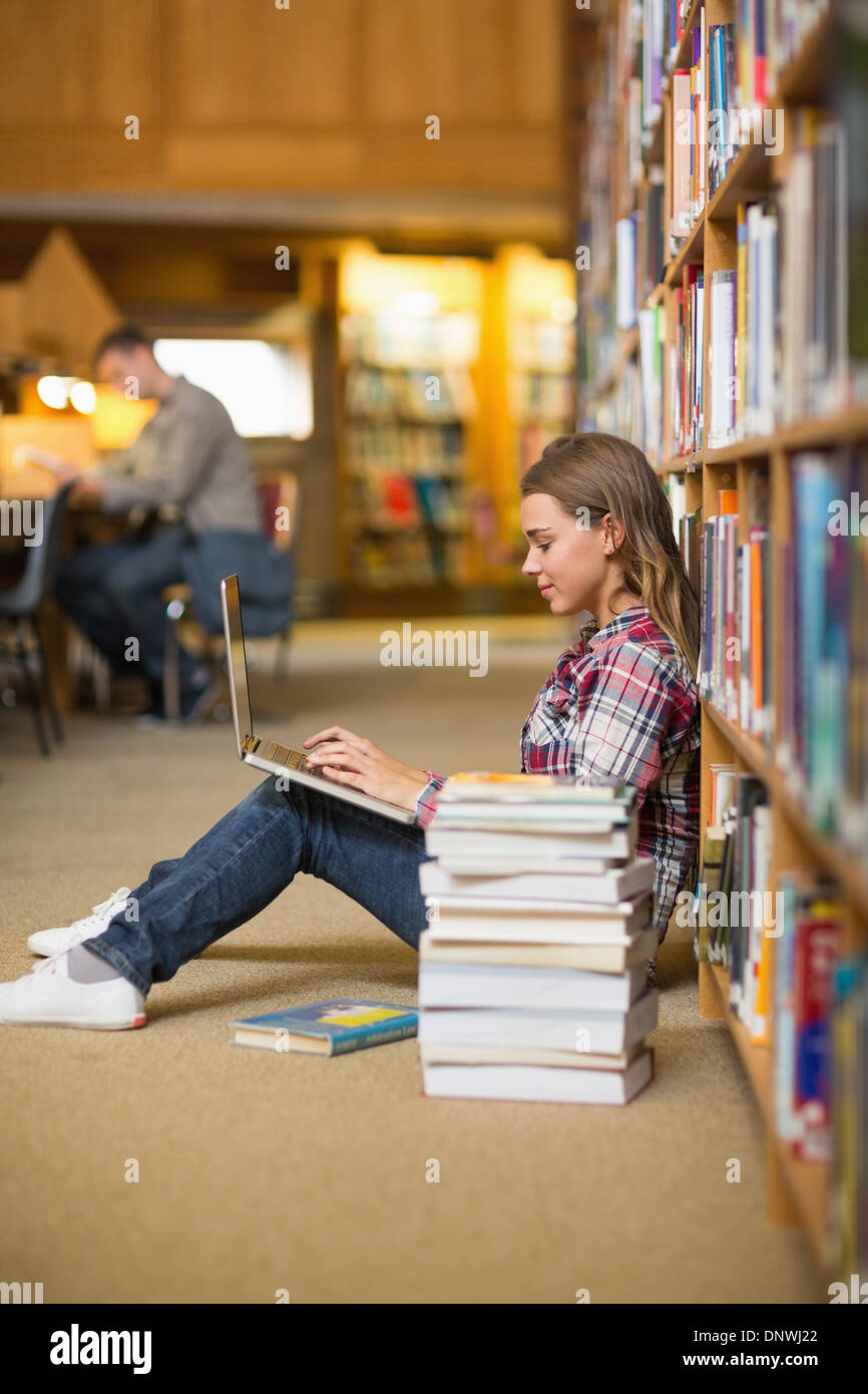 Pretty happy student using laptop on library floor Stock Photo - Alamy
