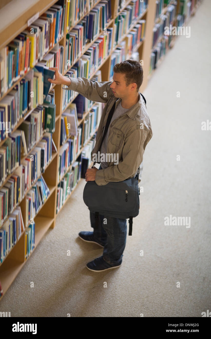 Student taking a book from shelf in library Stock Photo - Alamy