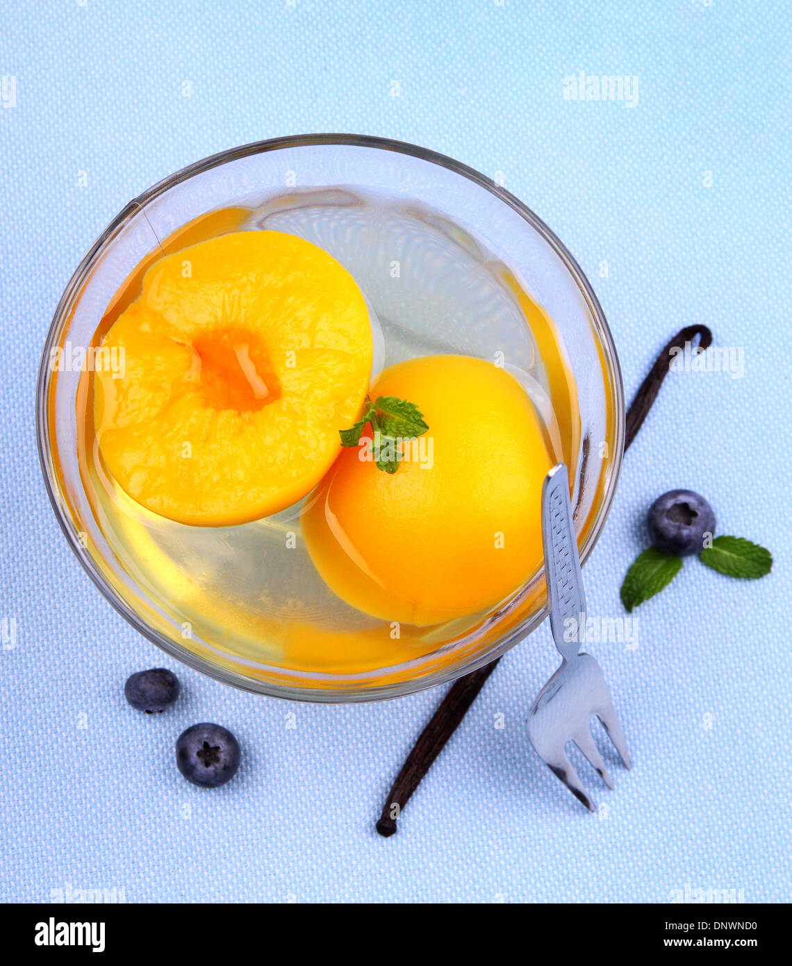 Peach compote in glass bowl with fork, blueberries and vanilla, top ...