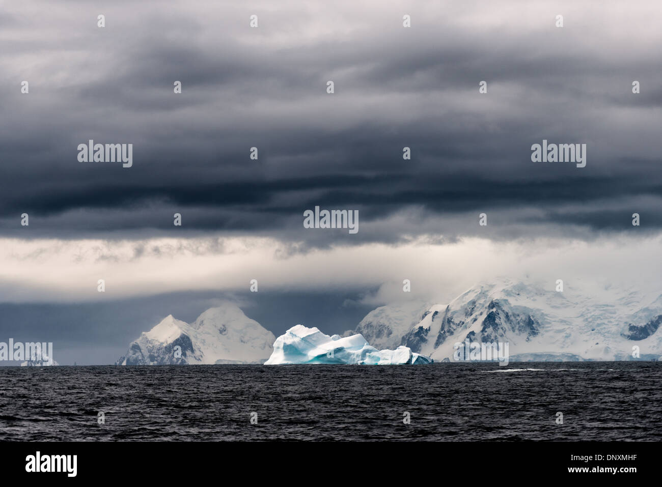 ANTARCTICA - A blue iceberg floats by the rugged mountains of the ...