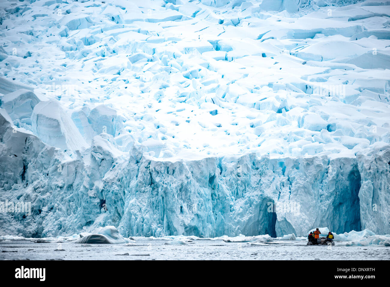 ANTARCTICA - Tourists in a Zodiac inflatable boat cruise past steep ...