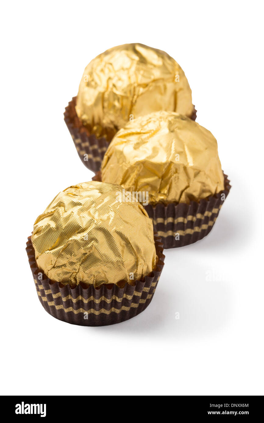 Three chocolate candies wrapped in golden foil isolated on white Stock ...
