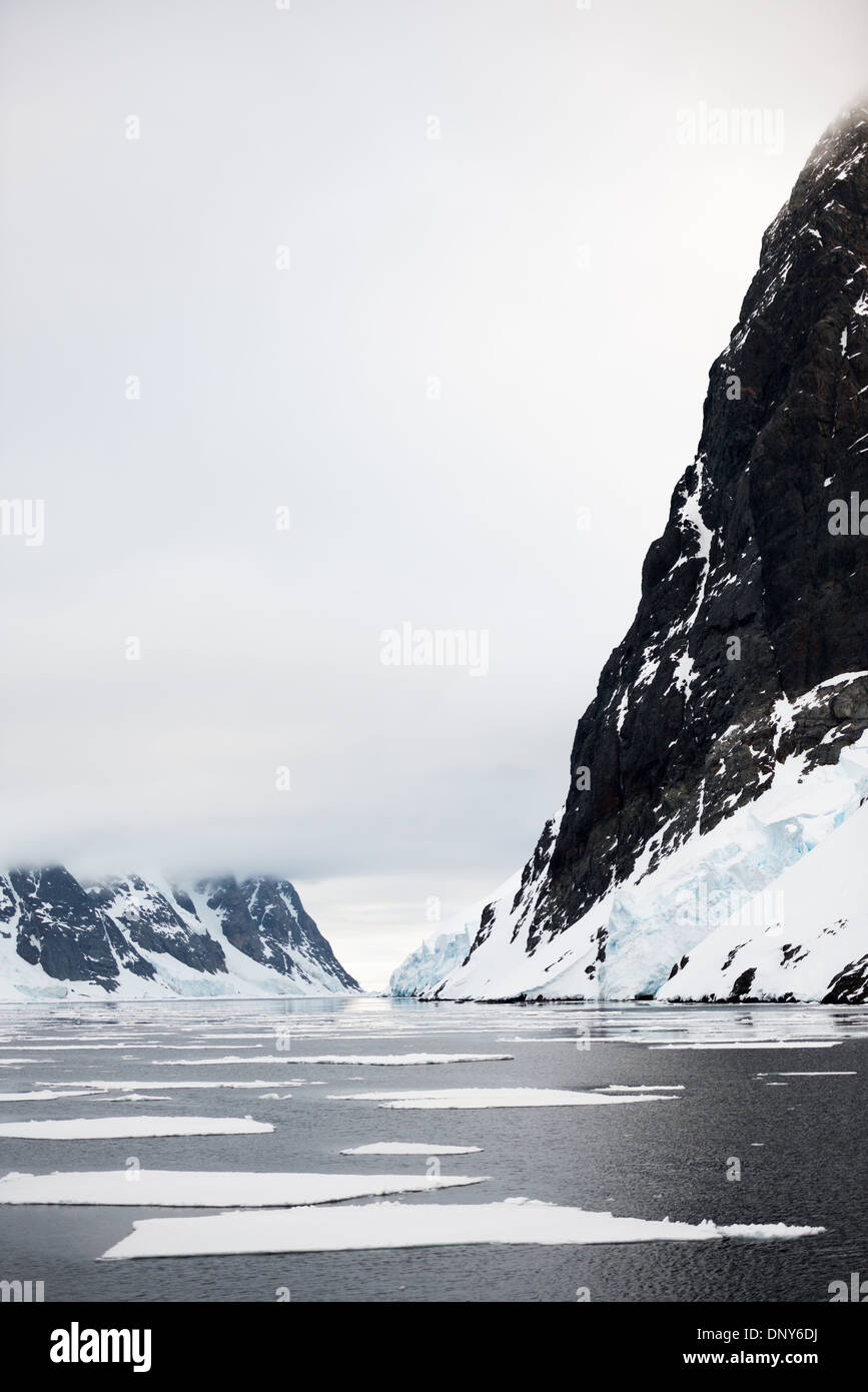 ANTARCTICA - Steep rocky cliffs rise out of the water along the narrow ...