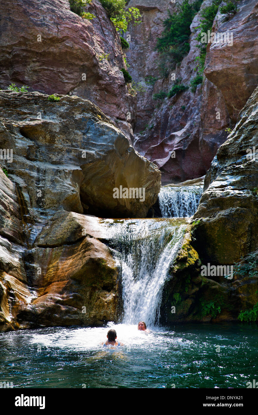 People swimming in a mountain stream feeding a sunlit rockpool in ...