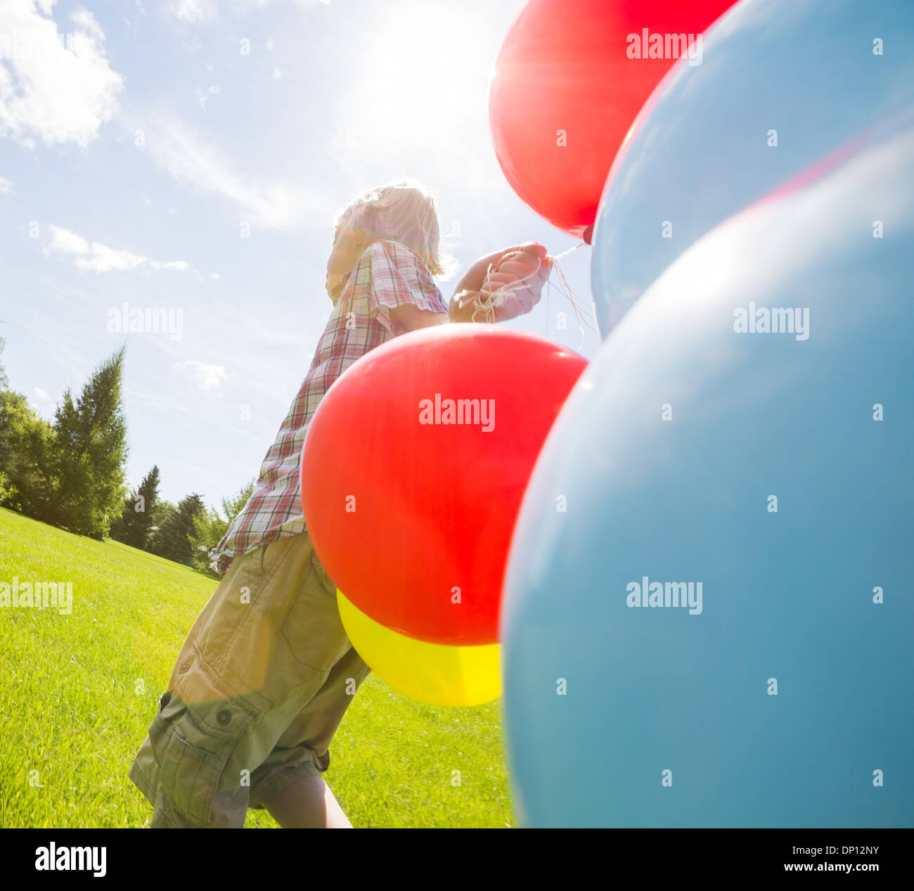 Boy With Balloons Walking In Green Meadow Stock Photo - Alamy