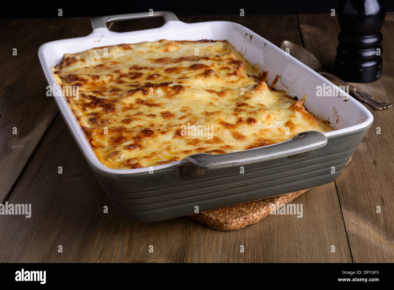 Lasagna in a serving plate with cheese on top on an old wood table ...