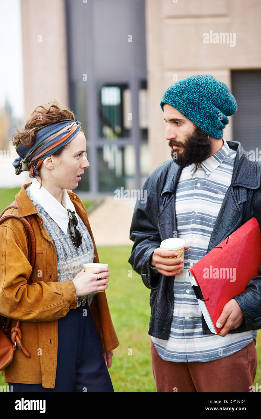 Hipster couple talking and drinking coffee to go at university campus ...