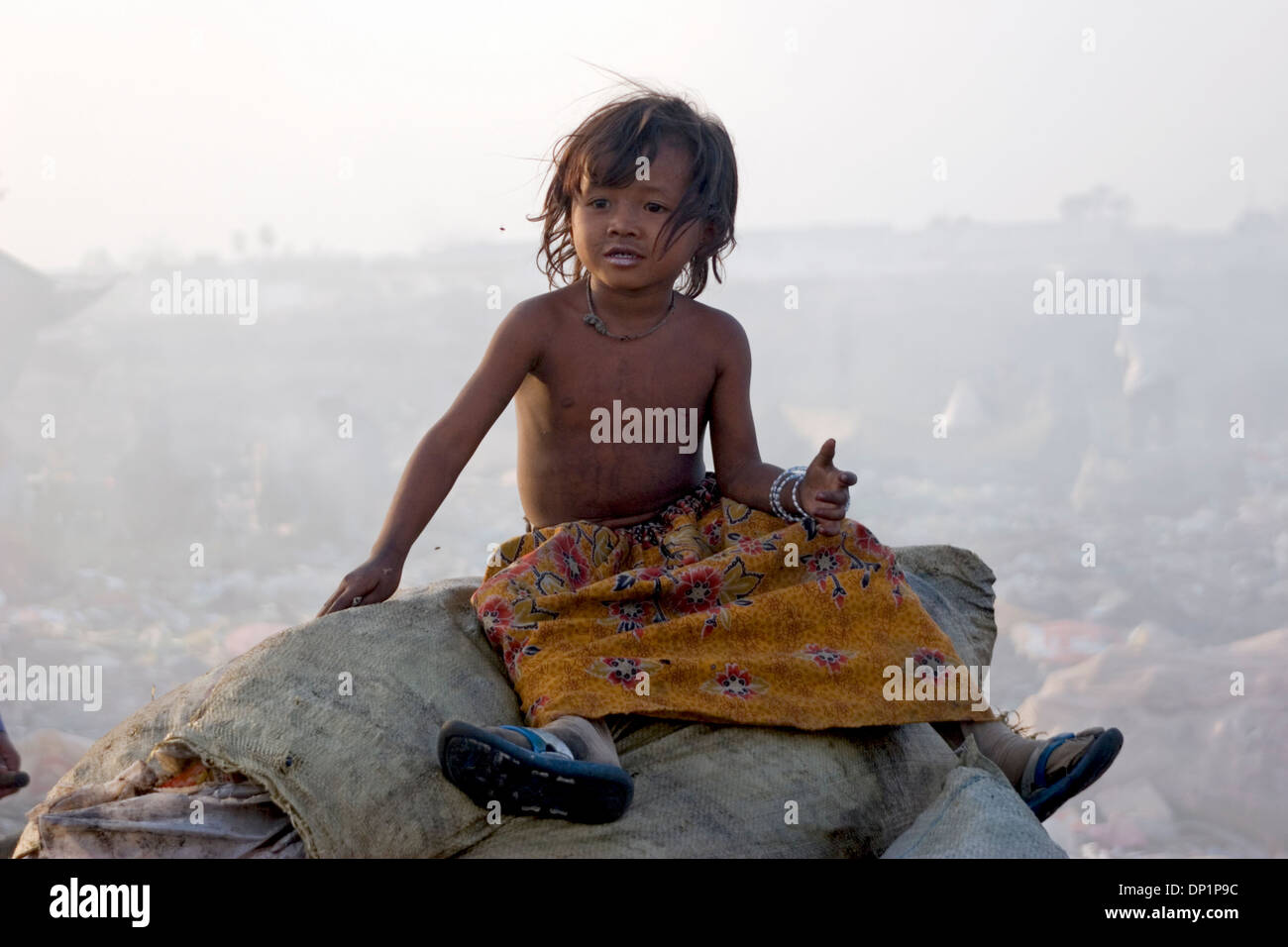 A child laborer girl who is a scavenger is sitting on a large sack at ...