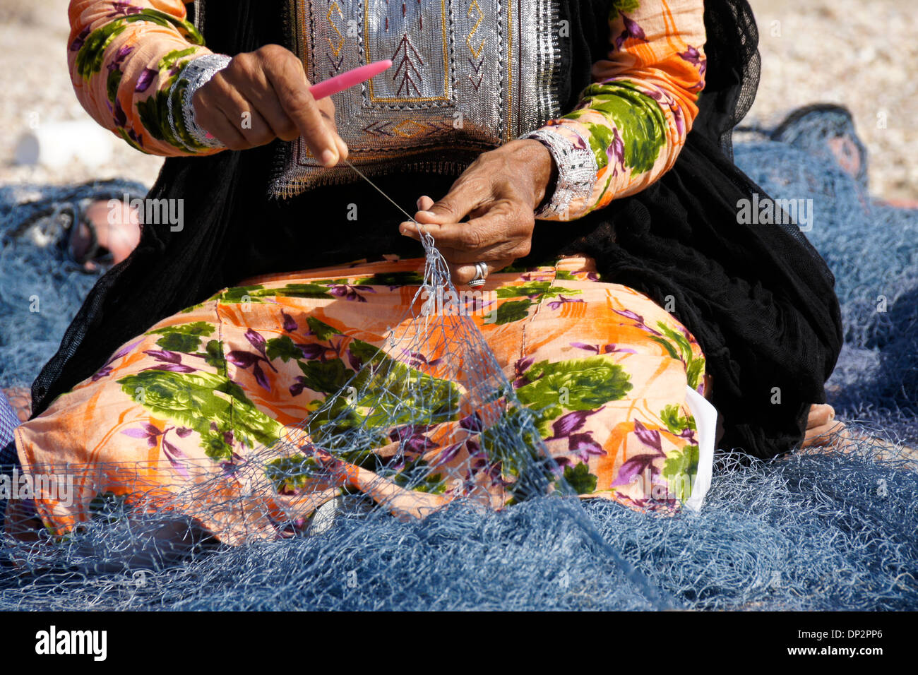 Woman mending fishing nets on beach, Sur, Oman Stock Photo - Alamy