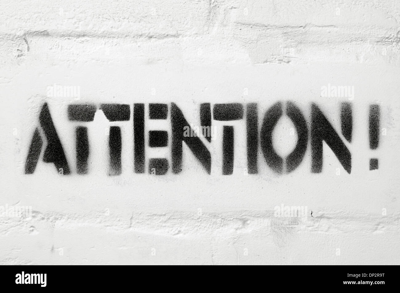 attention word textured stencil print on the white brick wall Stock ...