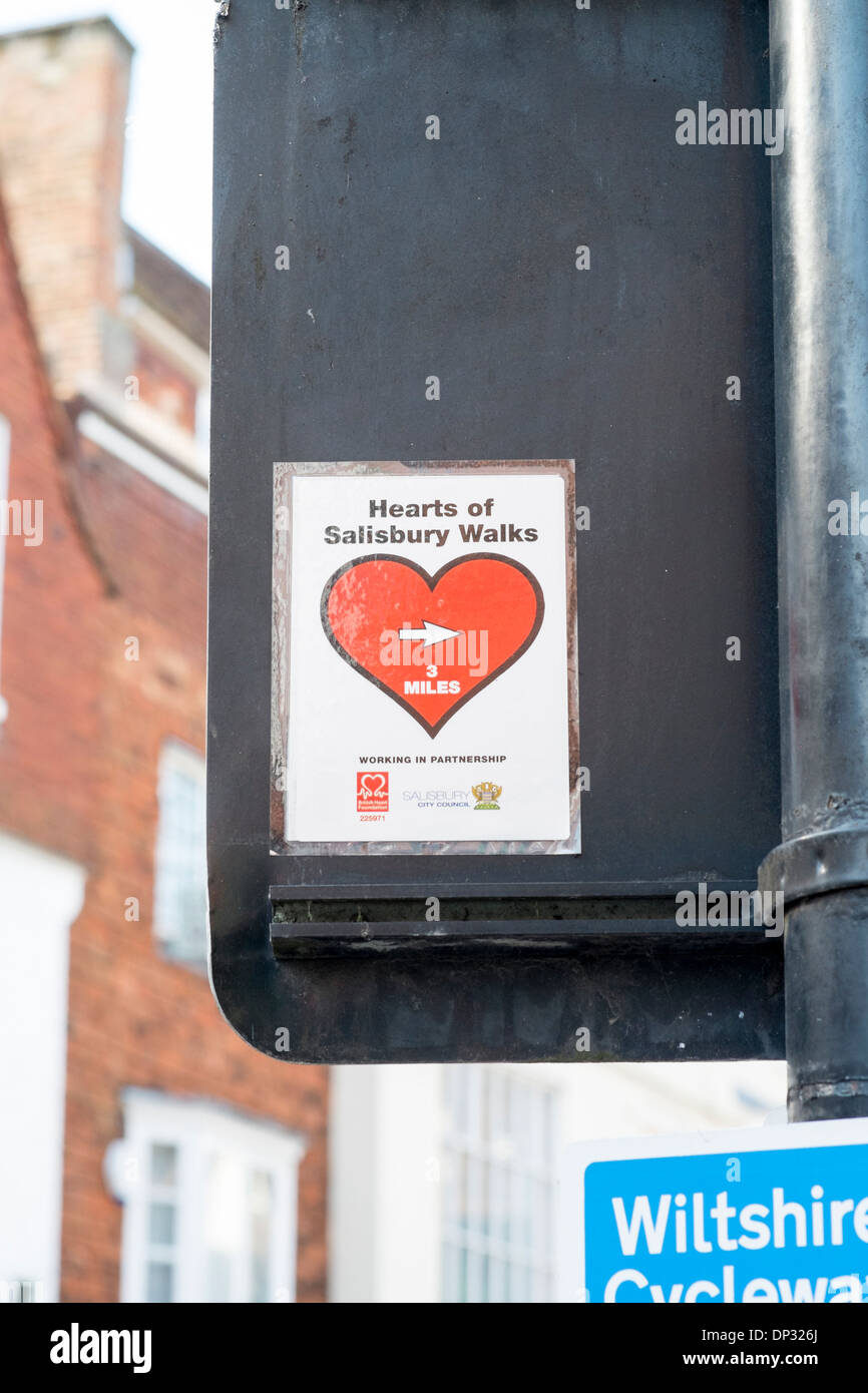 Red heart symbol on small sign indicating direction of a city walk ...