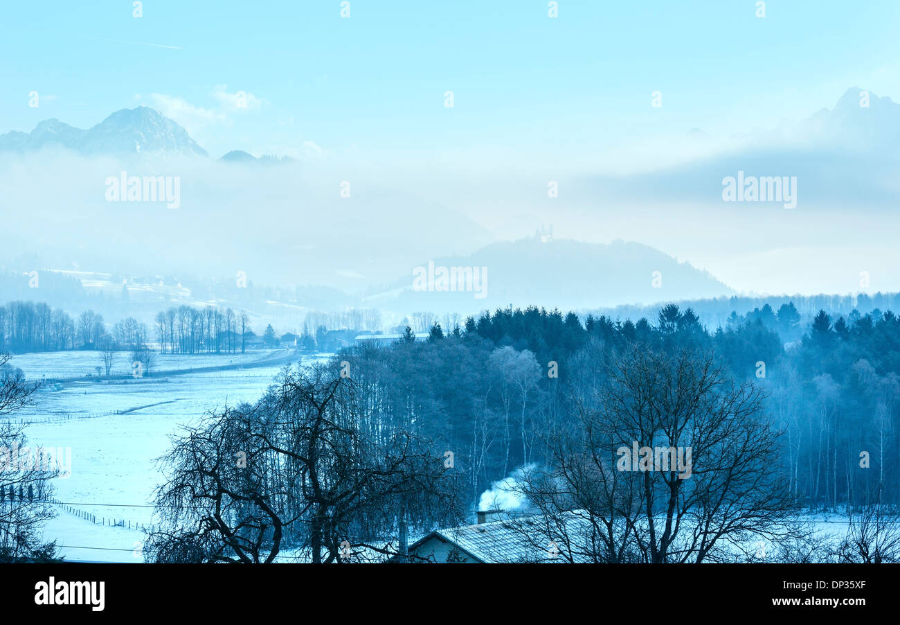 Winter morning mountain village hazy landscape with low-hanging clouds ...