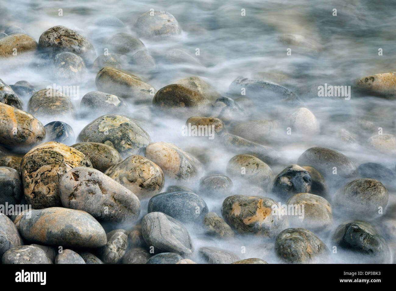 Pebbles on a beach with the sea lapping around them Stock Photo - Alamy