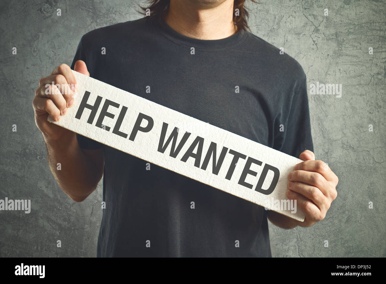 Casual man asking for help holding white board with title Help Wanted ...