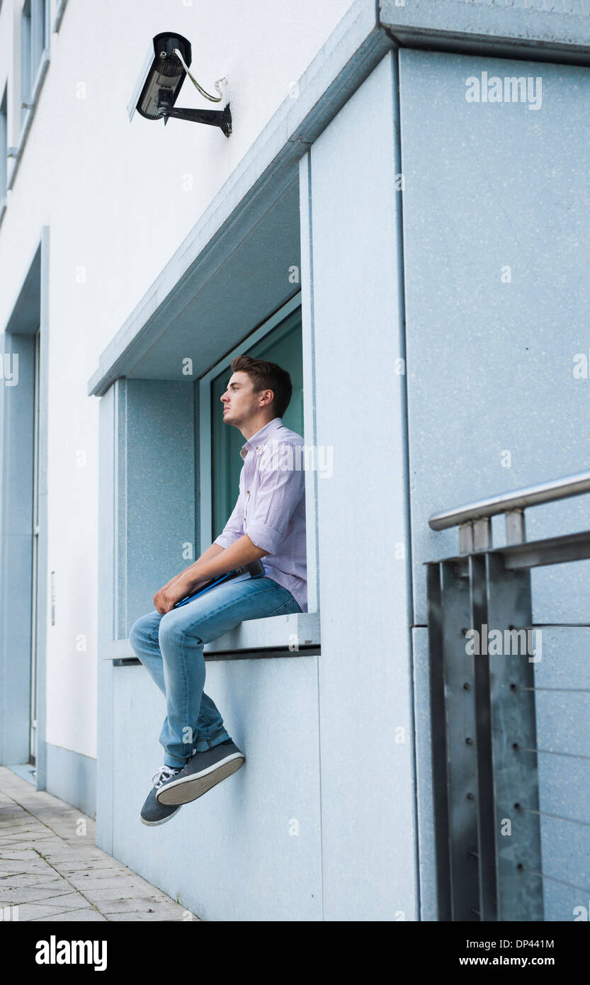 Young man sitting on ledge outdoors, Germany Stock Photo - Alamy