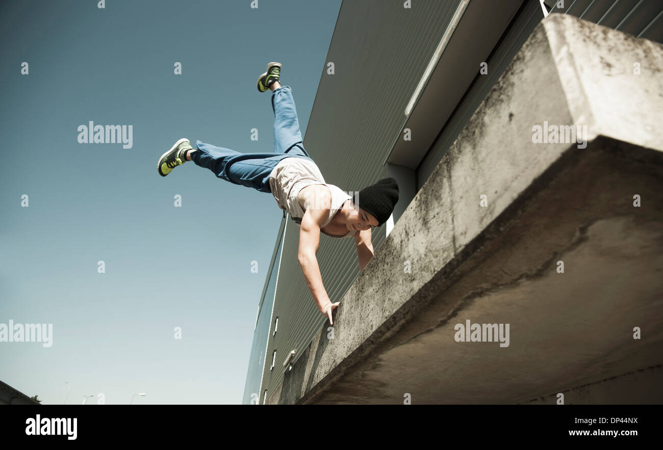 Low angle view of teenaged boy doing handstand on balcony, freerunning ...