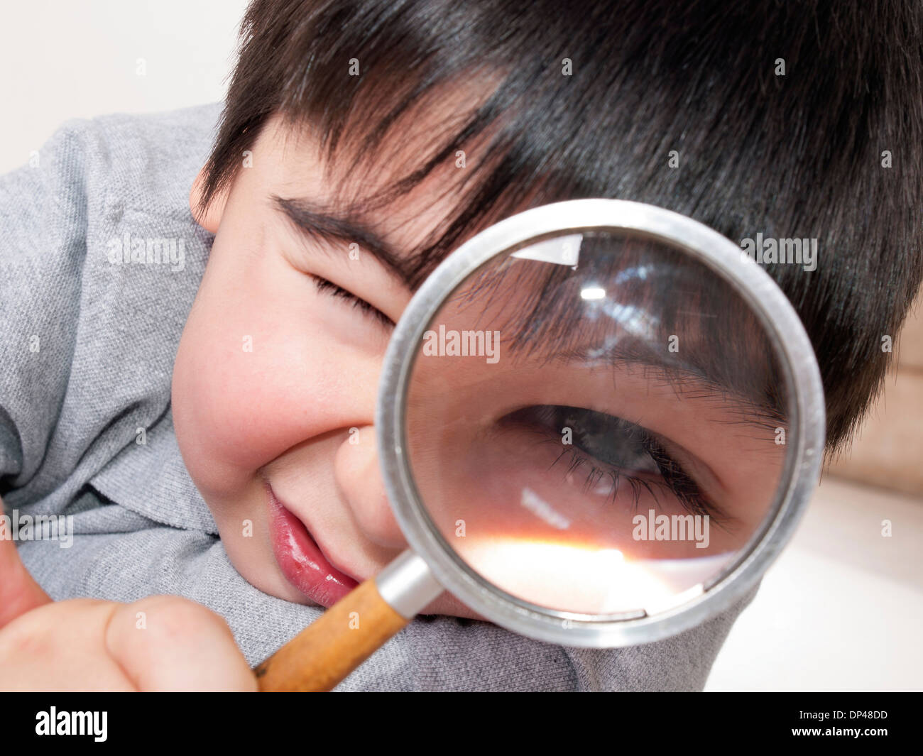 Boy looking through magnifying glass Stock Photo - Alamy