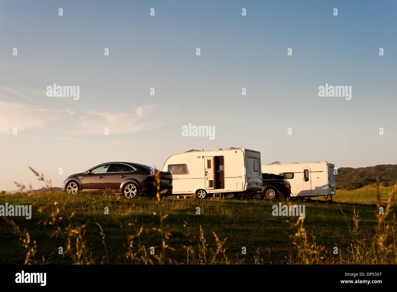 Car and caravans parked up in evening sunlight west coast Scotland ...